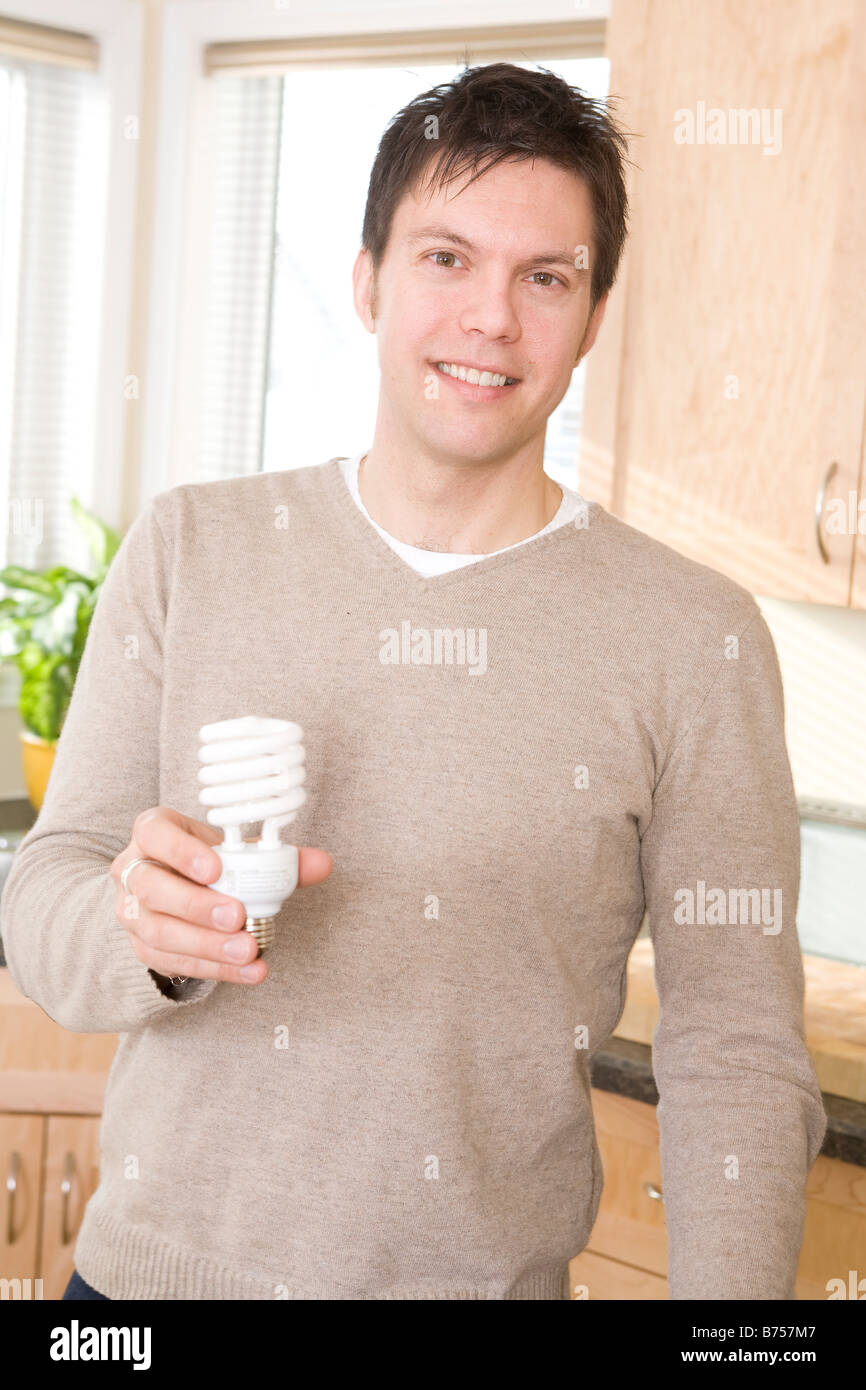 Man holding energy efficient compact fluorescent bulb, Winnipeg, Canada ...