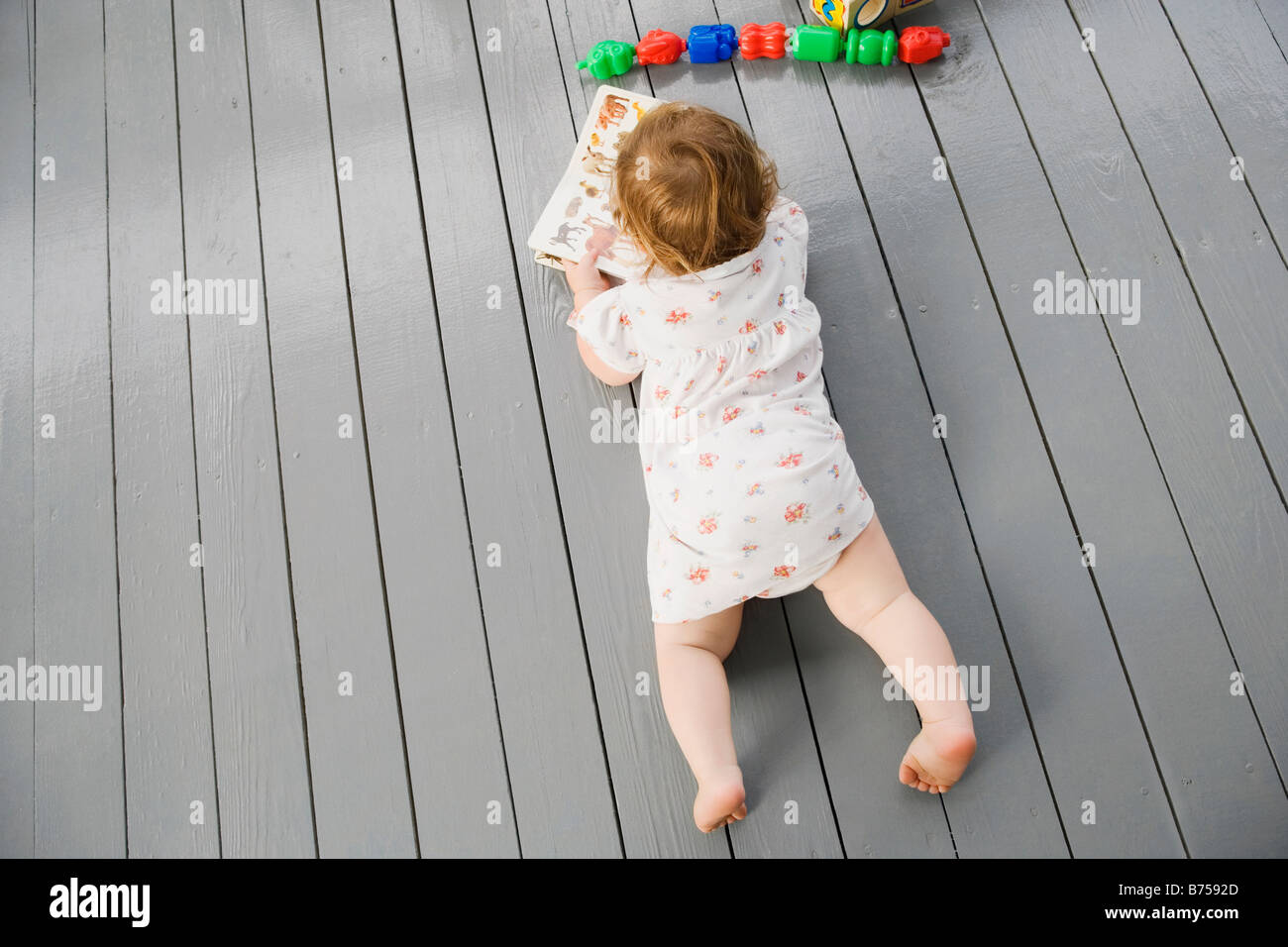 High angle view of a baby girl lying on the floor and looking at a ...