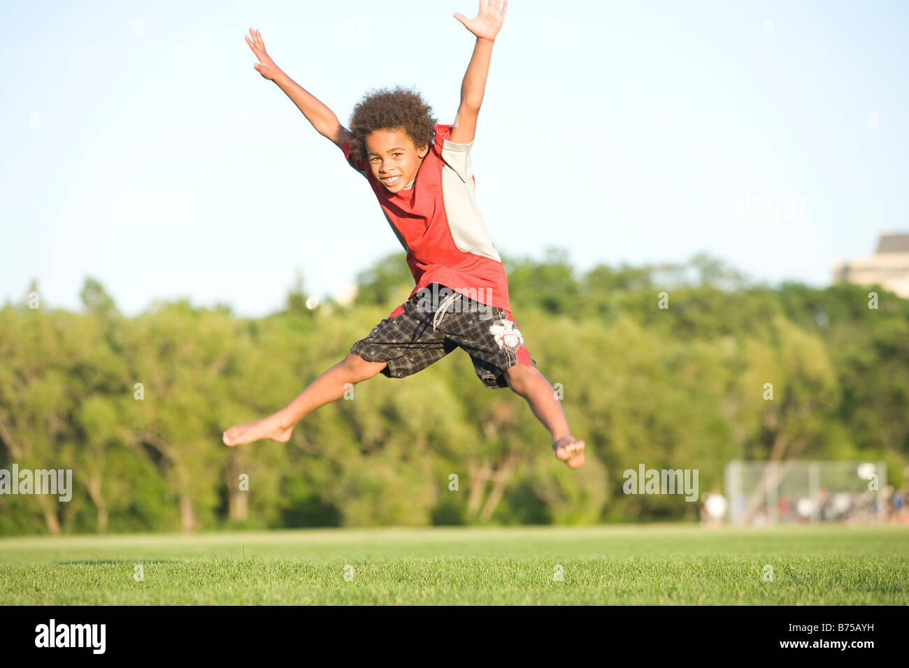 African-American 8 year old boy doing star jump, Winnipeg, Manitoba ...