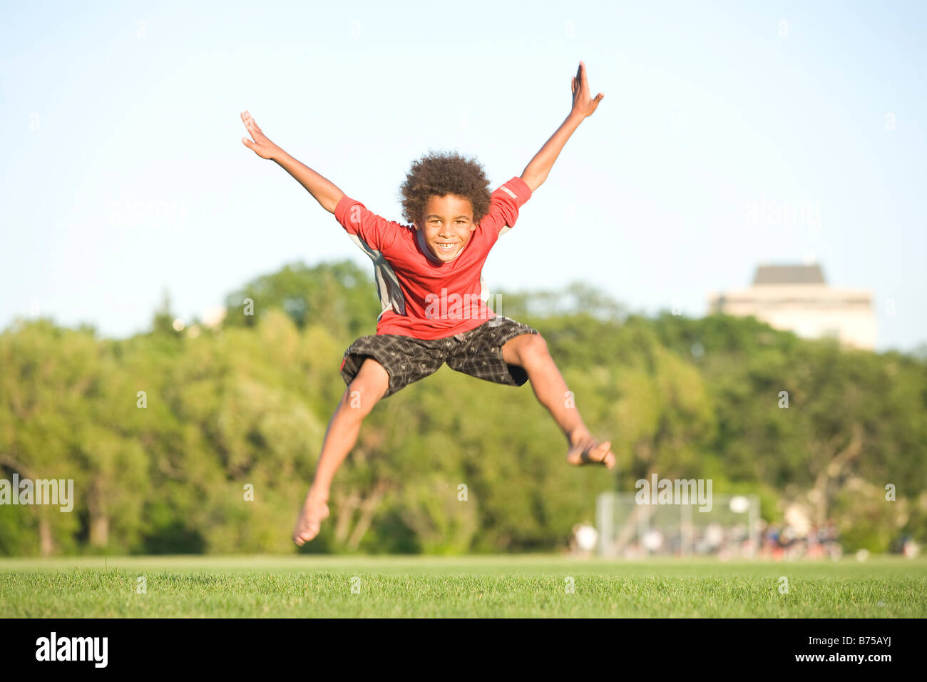 African-American 8 year old boy doing star jump, Winnipeg, Manitoba ...