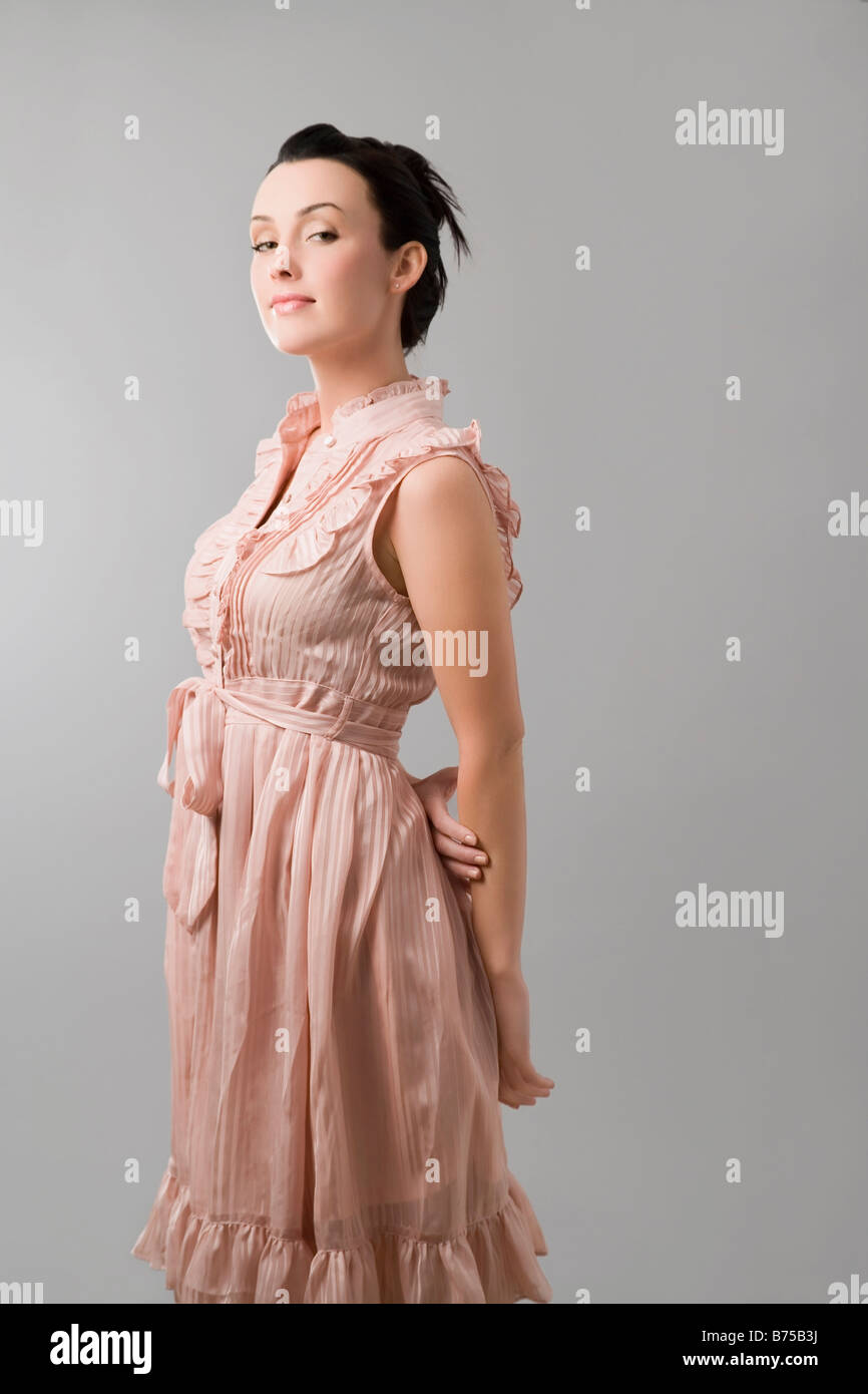 Portrait of a young woman standing with her hands behind her back Stock ...