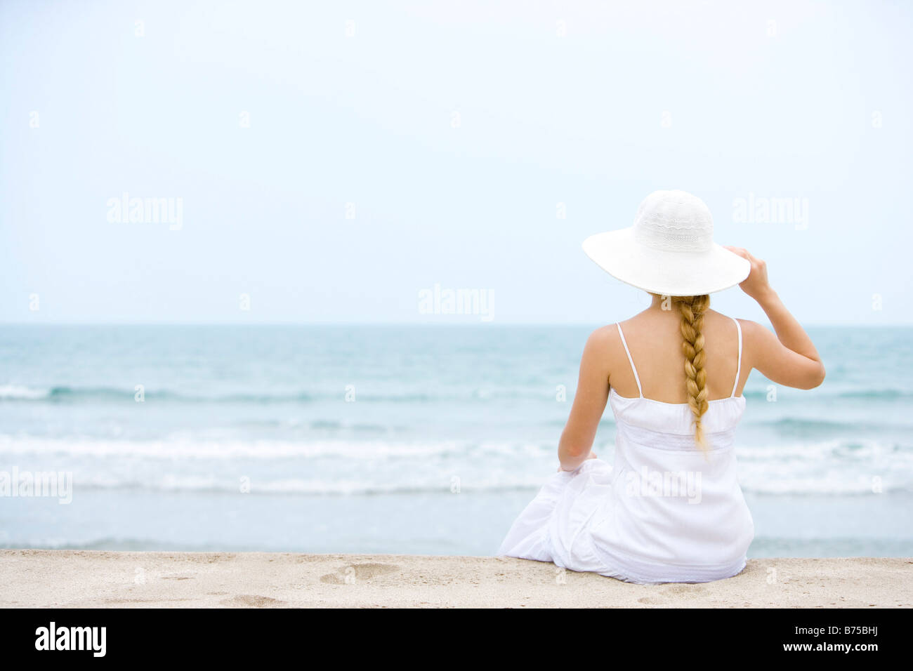 Young woman sitting on beach rear view Stock Photo - Alamy