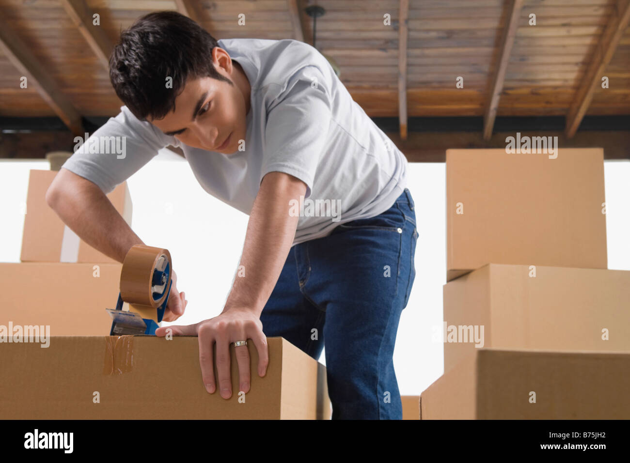 Young man pasting adhesive tape on a cardboard box Stock Photo - Alamy