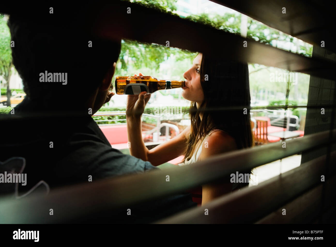 Side profile of a young woman drinking beer with a young man sitting ...
