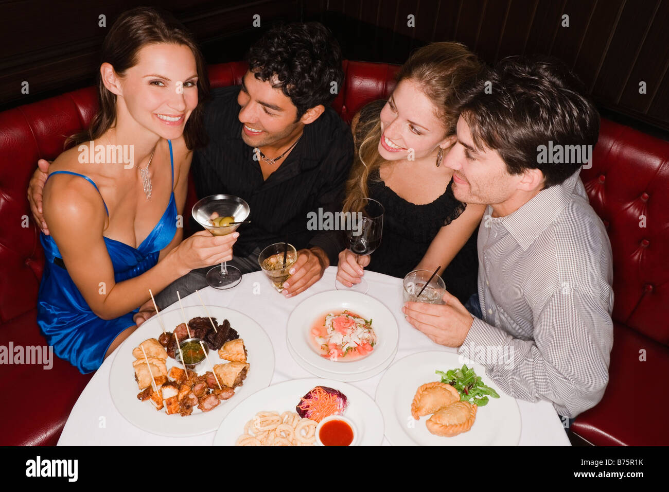 Two young couples sitting at a table in a restaurant and smiling Stock ...