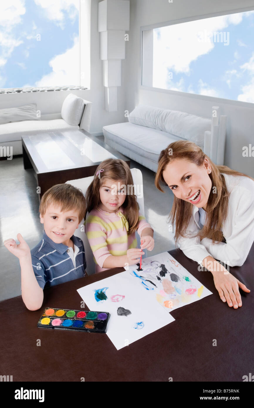 Portrait of a mid adult woman helping her children in painting Stock ...