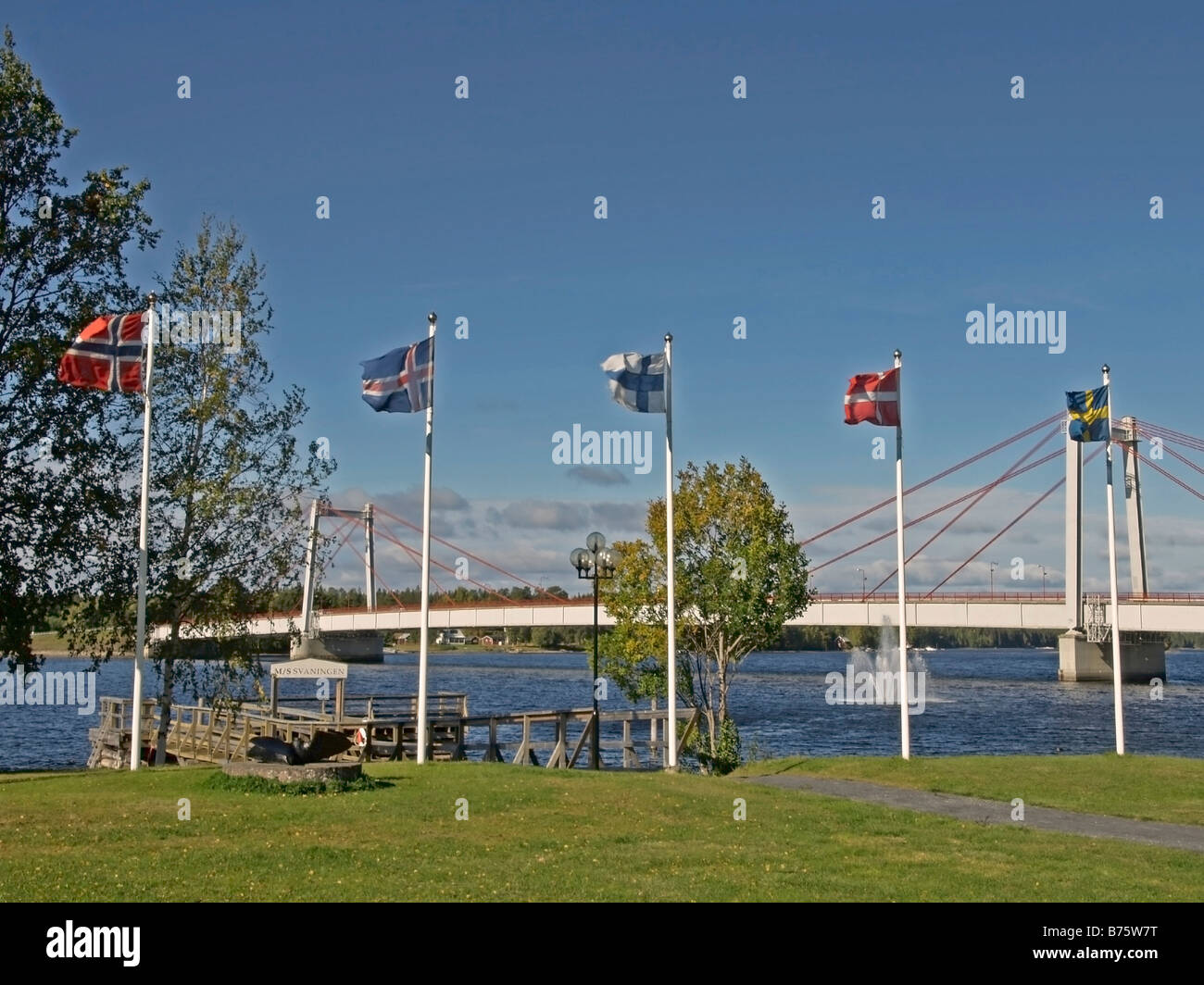 row of flags blowing in wind at a lake with flag of Norway Iceland ...