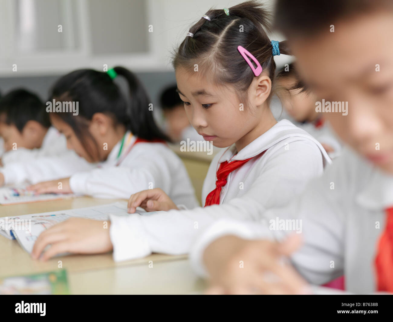A classroom of young students reading a lesson from their textbook ...