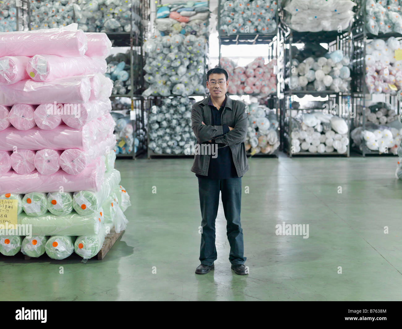 A portrait of an Chinese man inside a warehouse surrounded by thousands ...