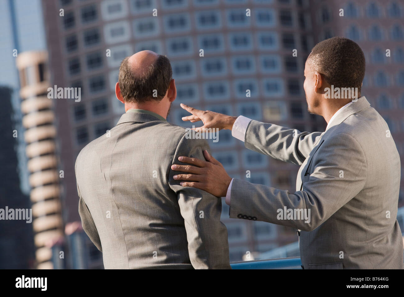 Two businessmen looking at office buildings, rear view Stock Photo - Alamy