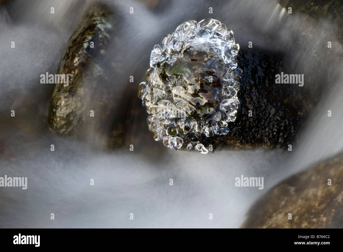 Ice formed on rocks in a mountain stream with water rushing past Stock ...