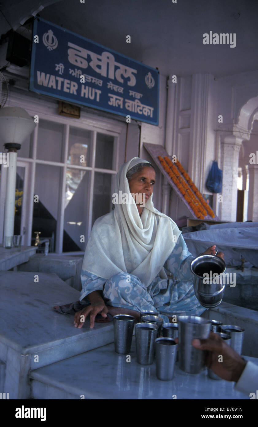 Sikh lady serving water to pilgrims at the Hari Mandir Golden Temple ...