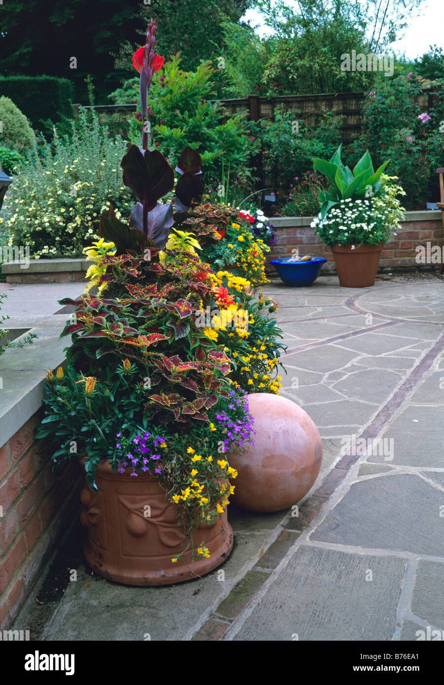 Terracotta ball and containers planted in hot colours on a stone ...