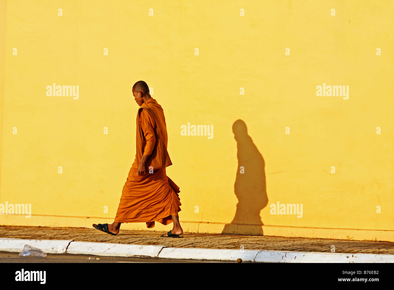 Buddhist monk in saffron robes walking in front of the Royal Palace ...
