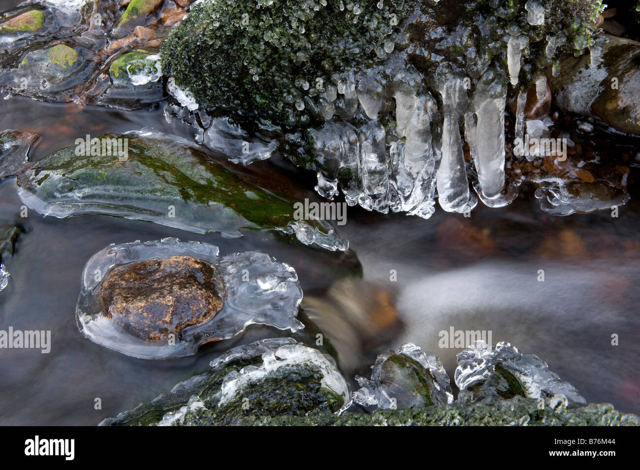 Ice formed on rocks in a mountain stream with water rushing past Stock ...