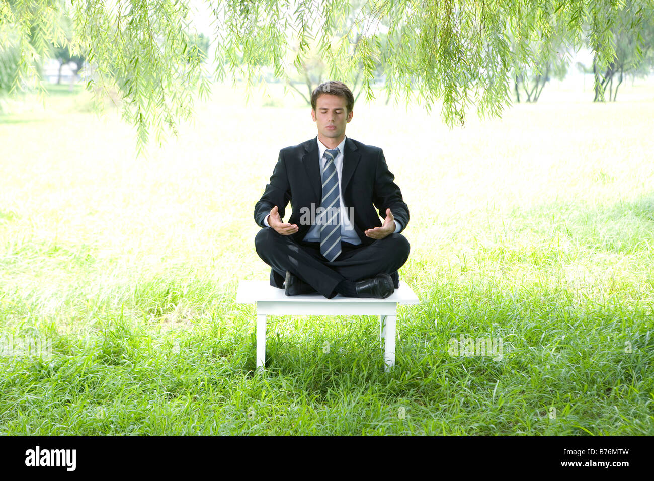 One mid adult man in lotus position sitting on desk outdoors Stock ...