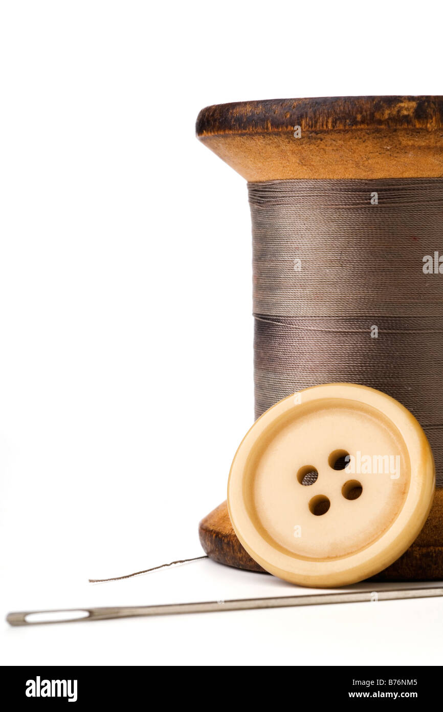 spool of thread needle and a button on white Stock Photo - Alamy