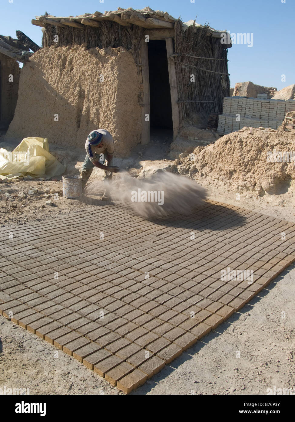 a Tunisian brickmaker in Tozeur dusts his latest batch of bricks before ...