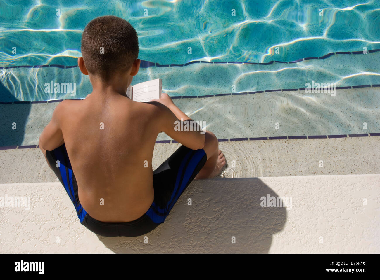 BOY READING BY POOL Stock Photo - Alamy