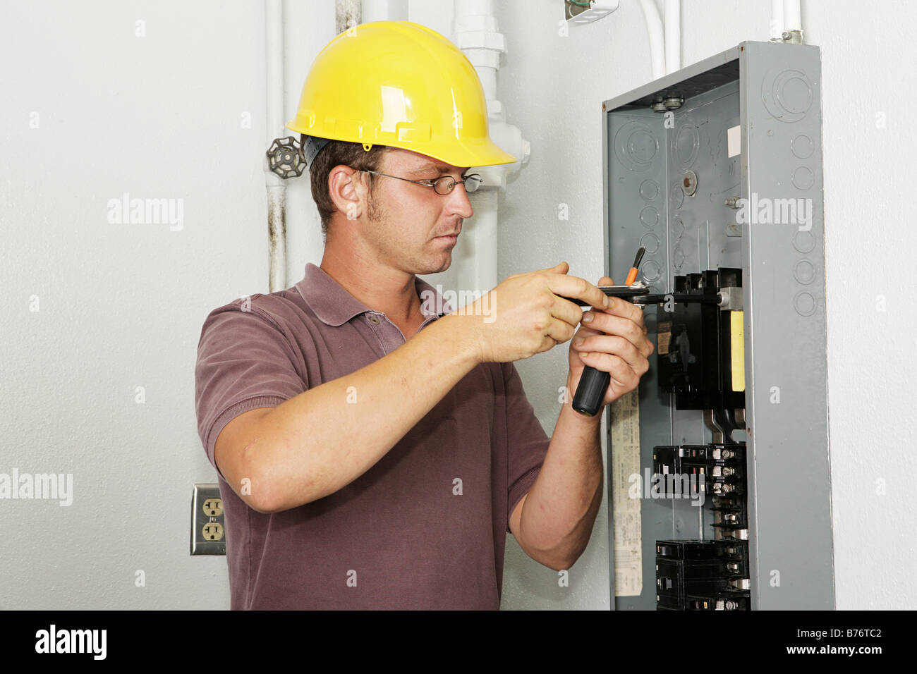 An electrician working on an industrial breaker panel Model is an ...