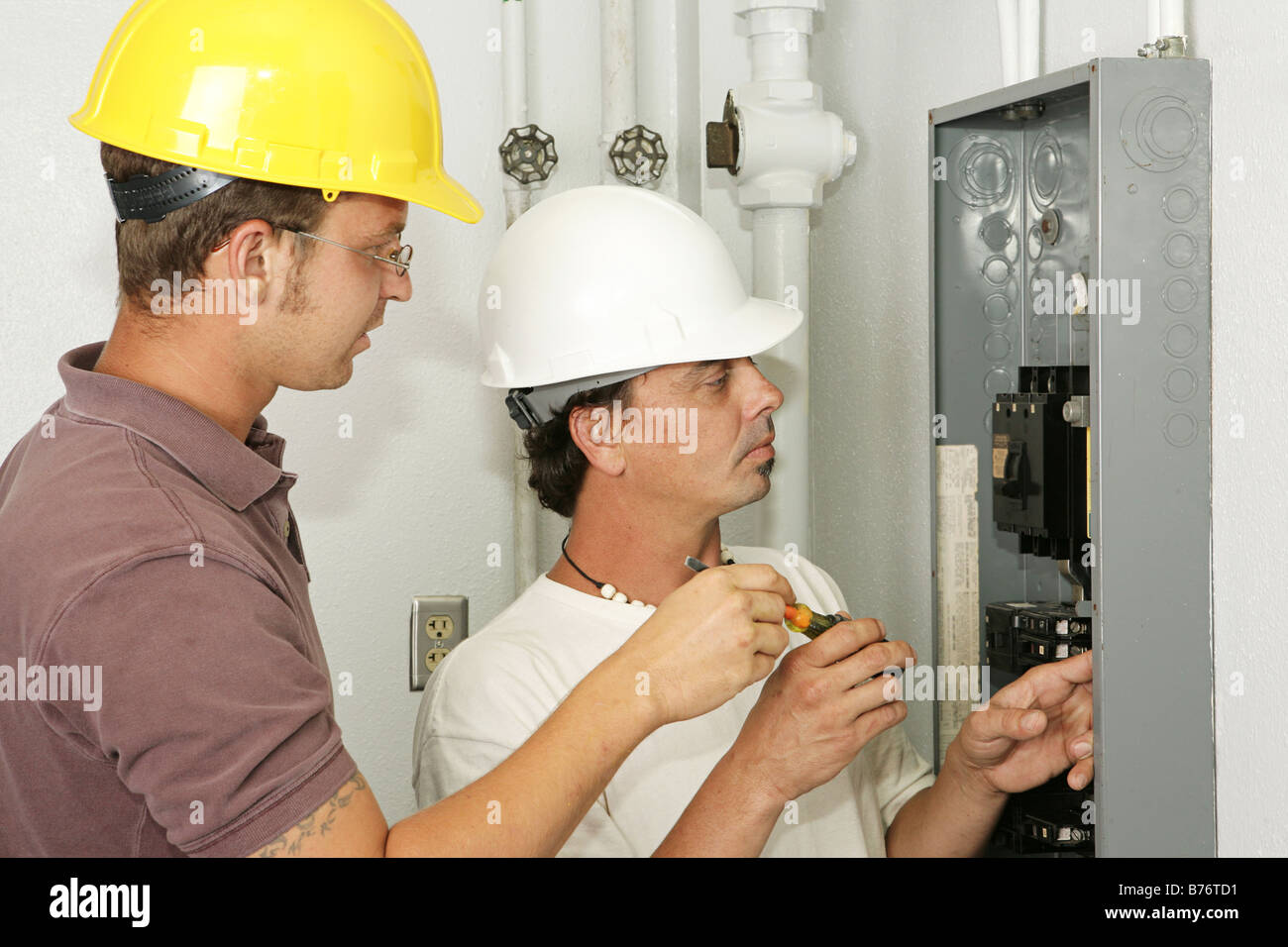 Electricians wiring an electrical breaker panel Models are professional ...