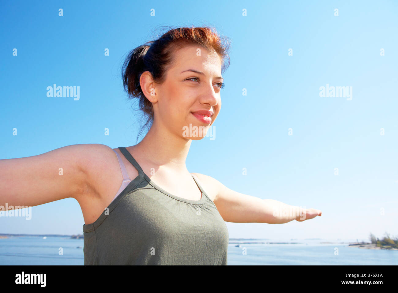 Teenage girl stretching her arms by sea Stock Photo - Alamy