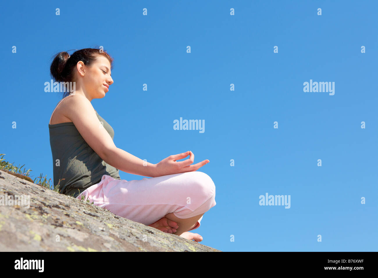 Teenage girl meditating on rock, side view Stock Photo - Alamy