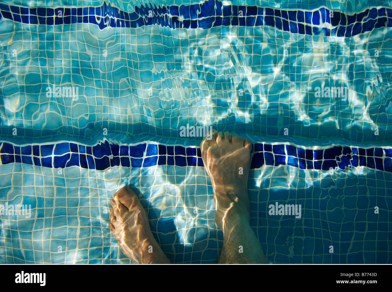 Swimming pool edge with pair of feet in water Stock Photo - Alamy