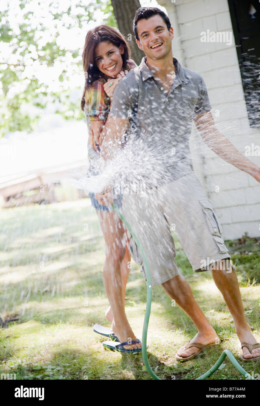 Portrait of couple spraying hose backyard Stock Photo - Alamy