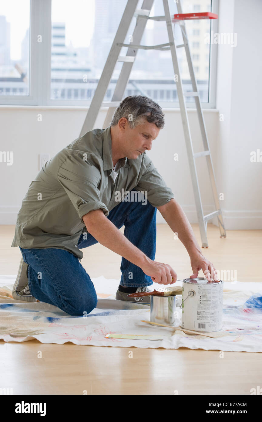 Man opening paint cans on drop cloth Stock Photo - Alamy