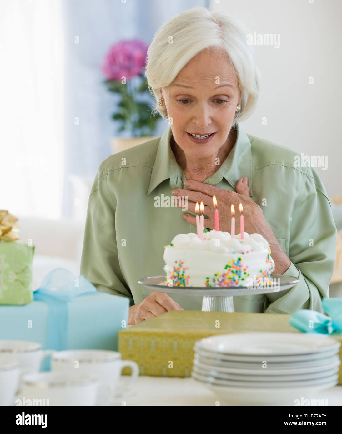 Senior woman looking birthday cake Stock Photo - Alamy