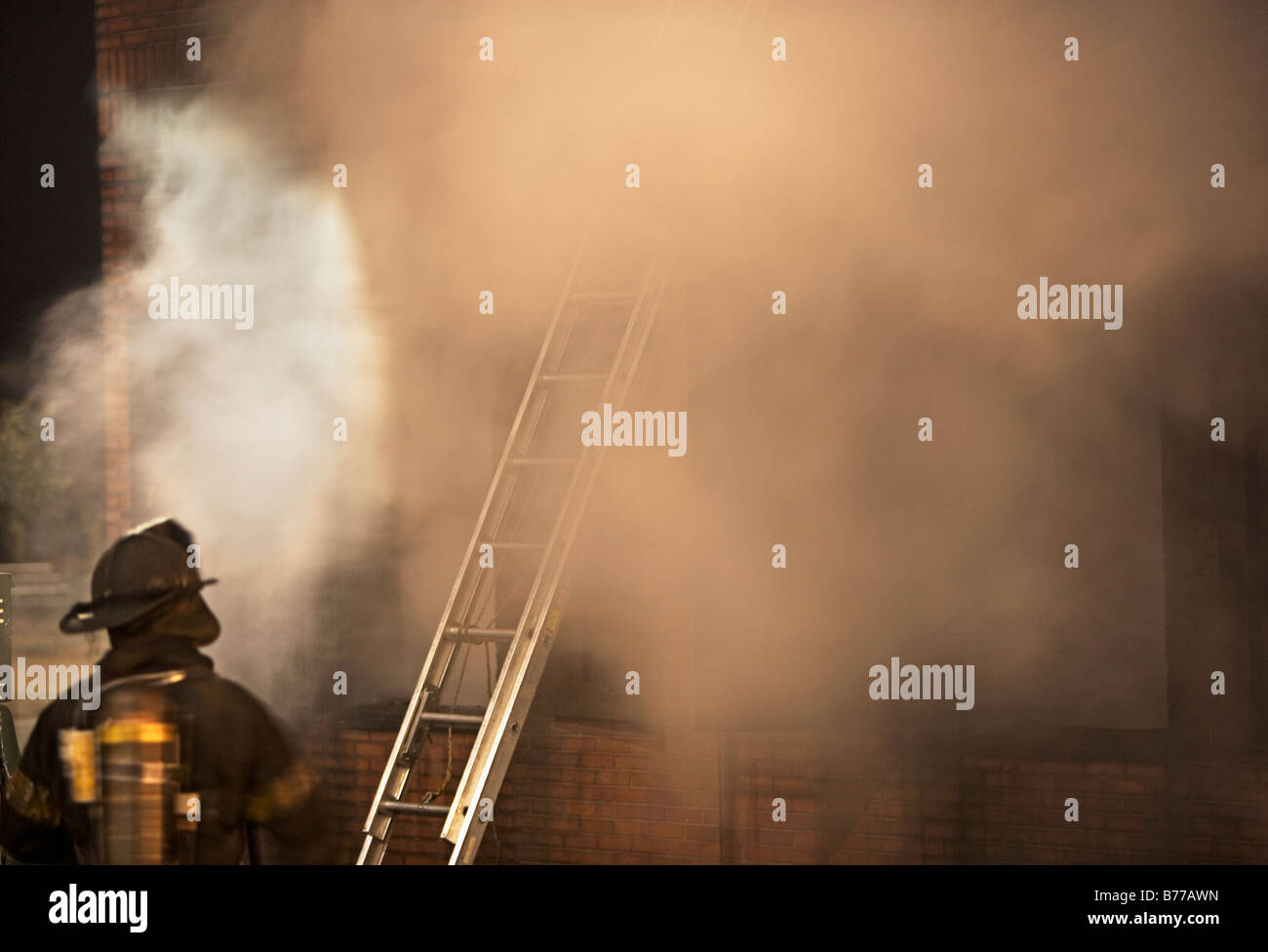 Firefighter standing outside burning building Stock Photo - Alamy