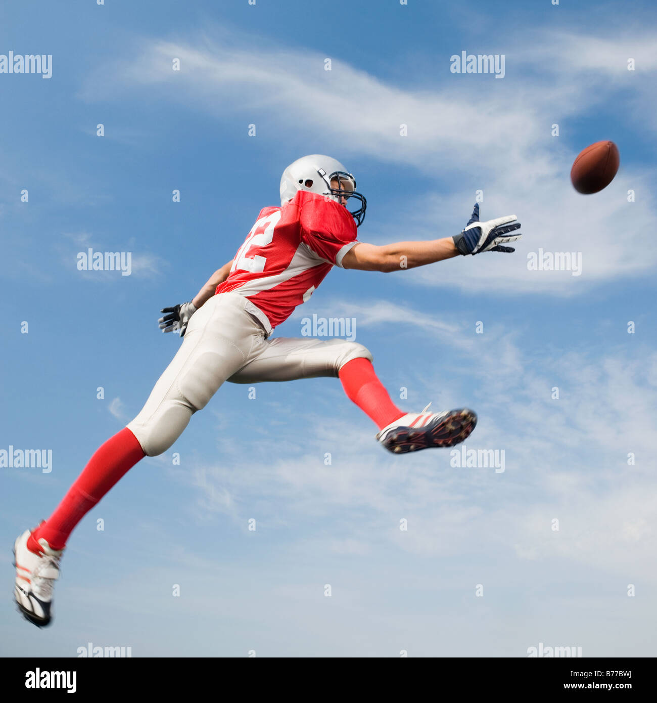Football player mid-air reaching for football Stock Photo - Alamy