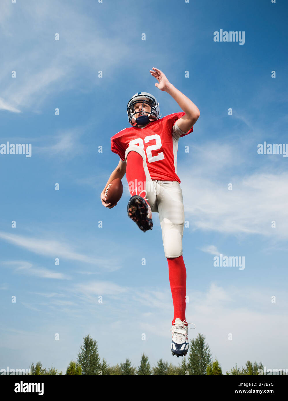Football player mid-air holding football Stock Photo - Alamy