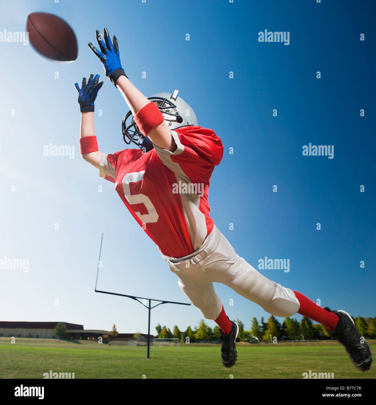 Football player mid-air reaching for football Stock Photo - Alamy