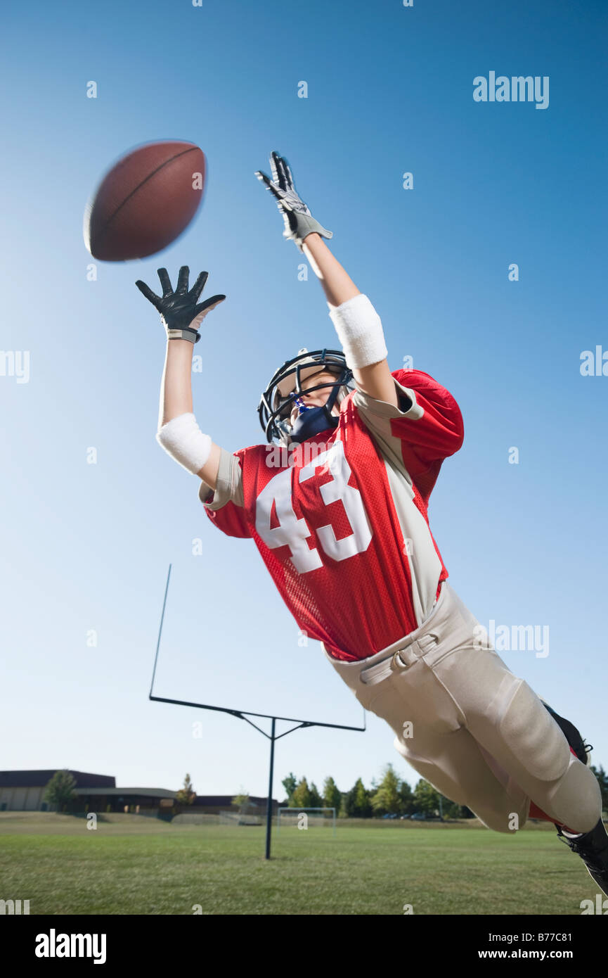 Football player mid-air reaching for football Stock Photo - Alamy