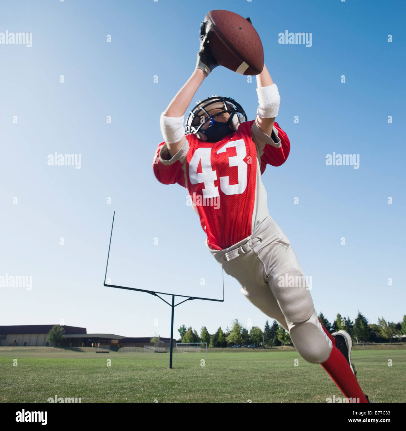 Football player mid-air reaching for football Stock Photo - Alamy