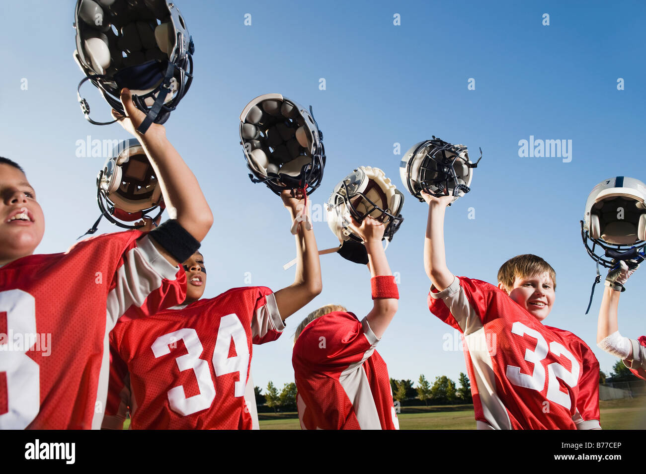 Football team holding helmets overhead Stock Photo - Alamy