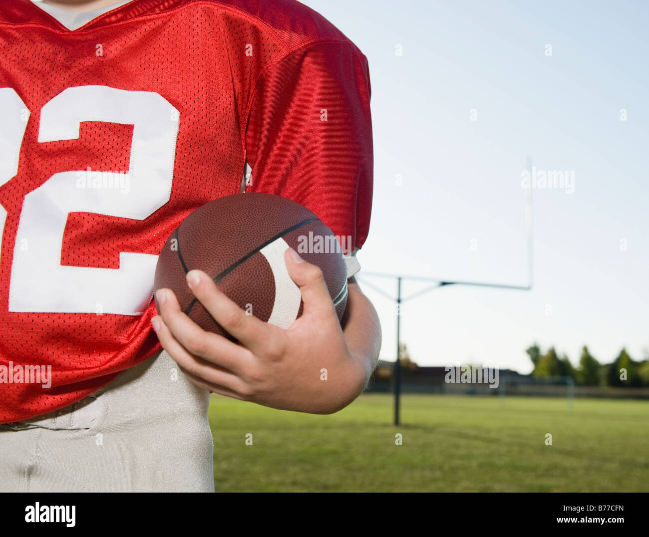 Close up of football player holding football on field Stock Photo - Alamy