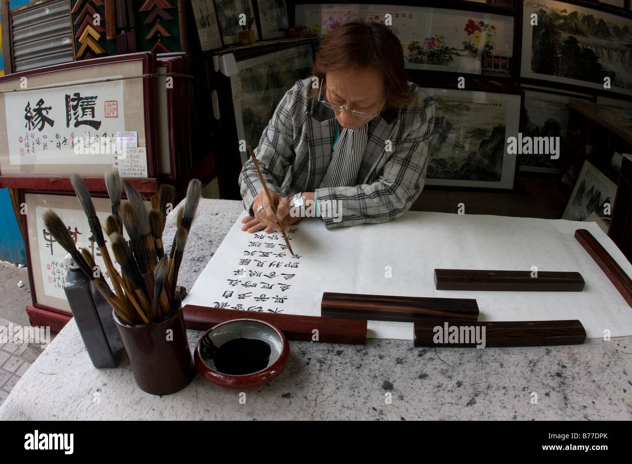 Chinese artiest and shop owner sitting creating a new artwork piece ...