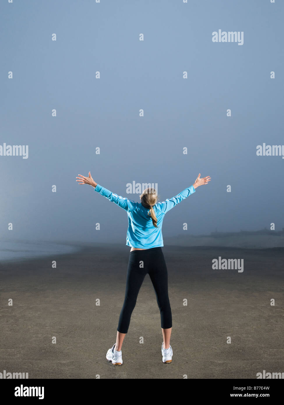 Woman arms outstretched on foggy beach Stock Photo - Alamy