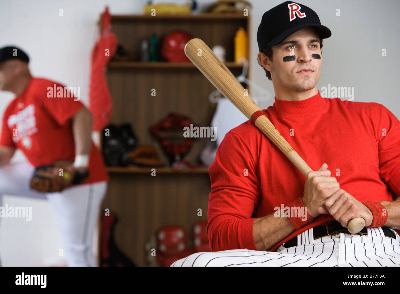 Baseball player holding bat locker room Stock Photo - Alamy