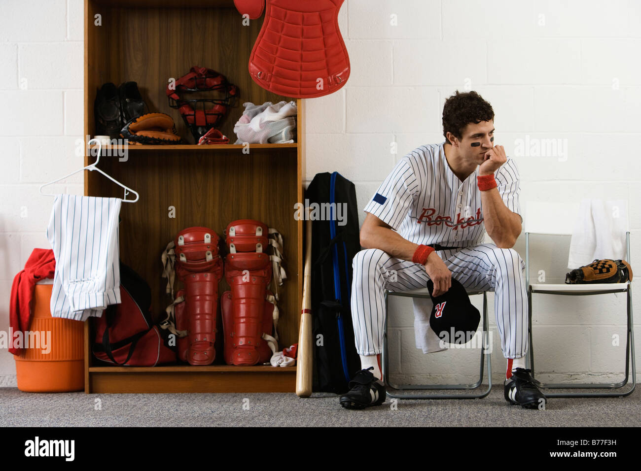 Baseball player sitting locker room looking pensive Stock Photo - Alamy