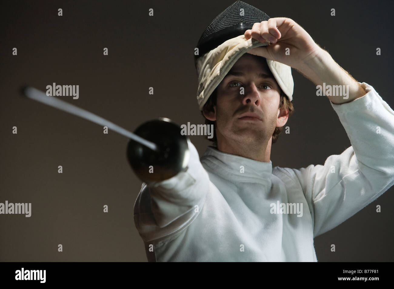 Man pointing fencing foil and lifting mask Stock Photo - Alamy