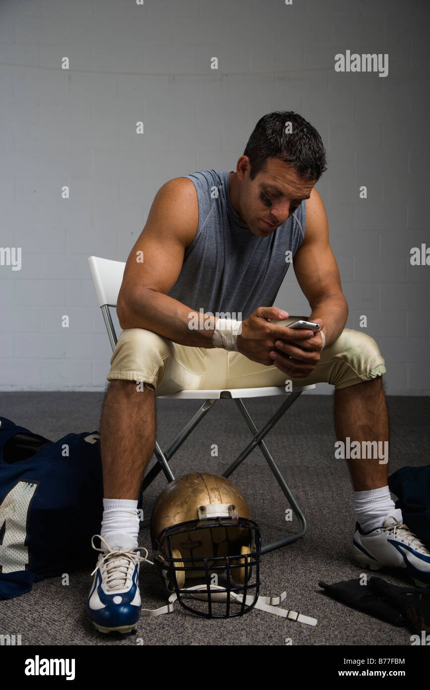 Football player looking cell phone locker room Stock Photo - Alamy