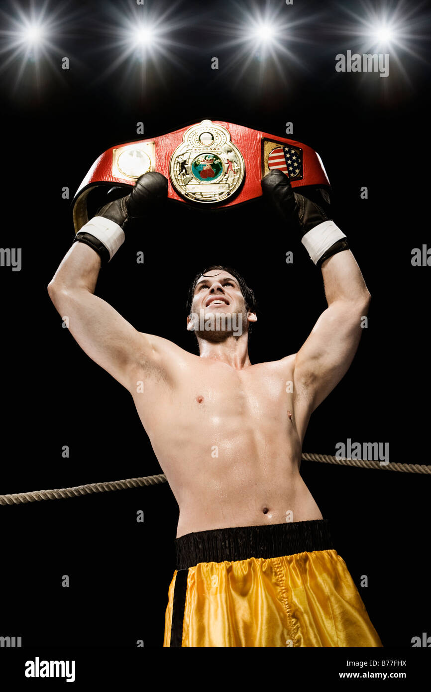 Boxer holding championship belt overhead boxing ring Stock Photo - Alamy