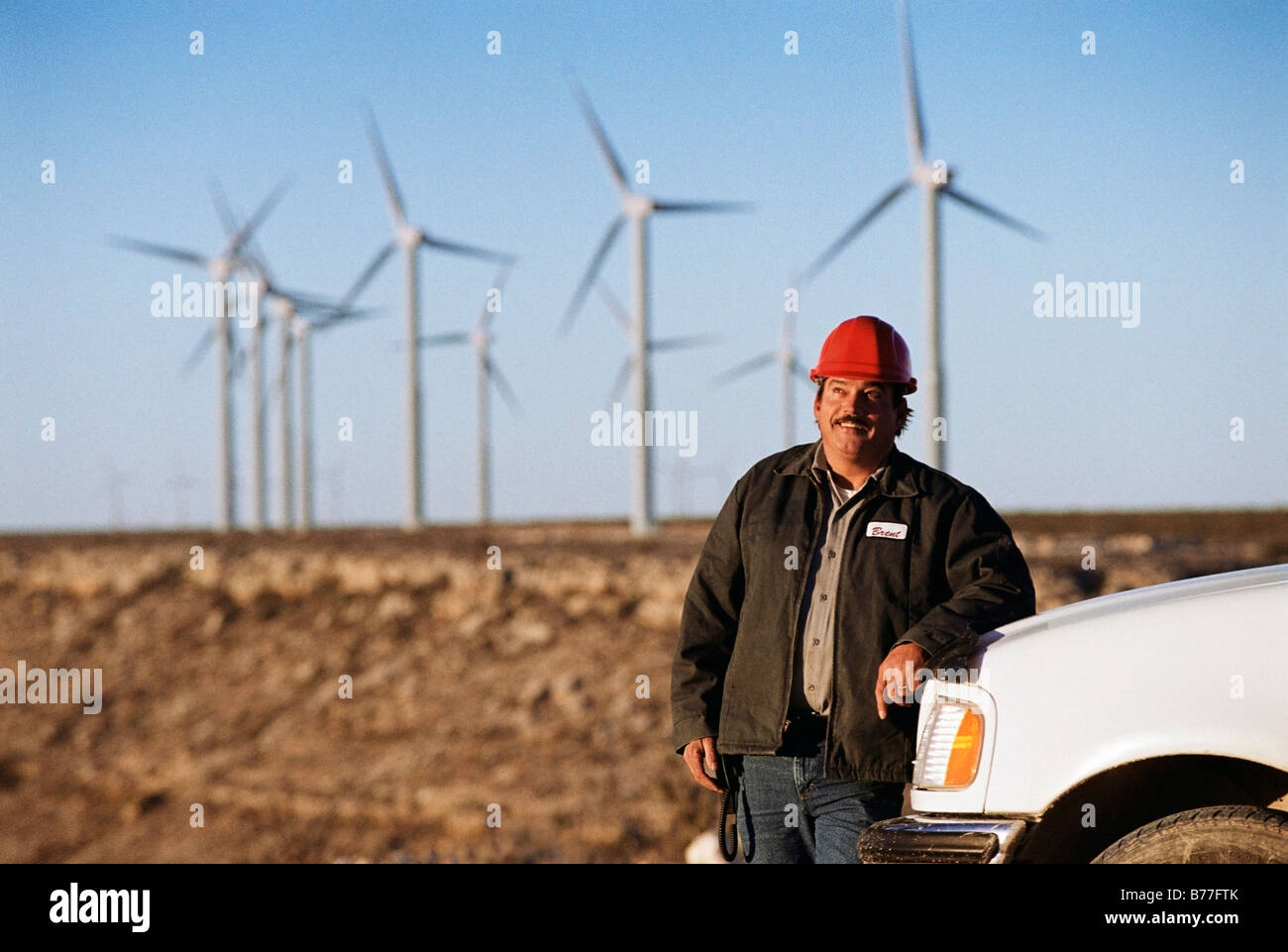 Worker leaning against truck wind turbines background Stock Photo - Alamy
