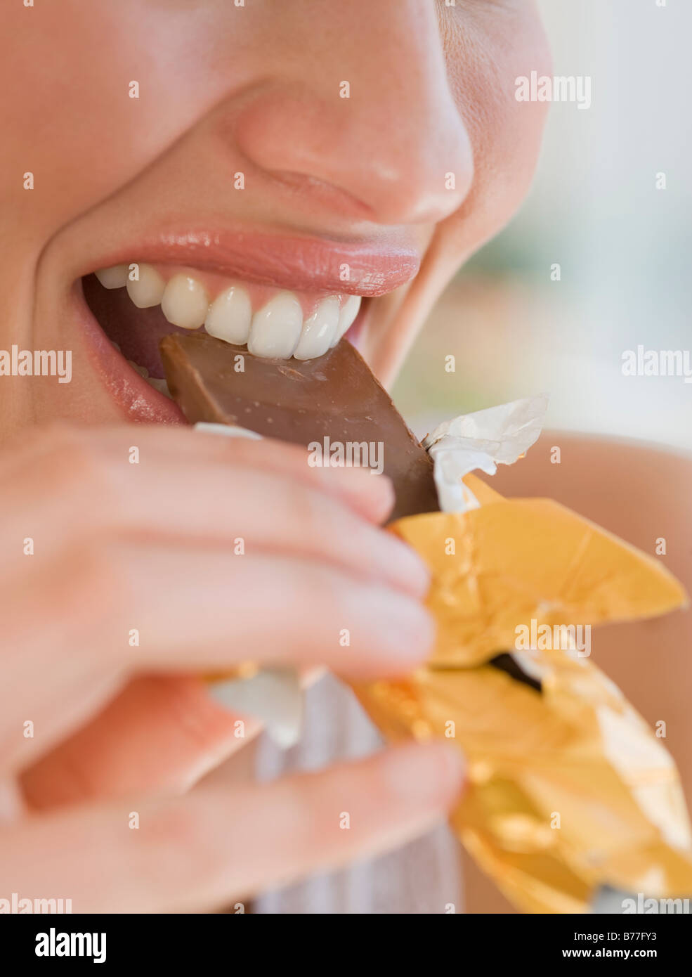 Close up of woman biting chocolate bar Stock Photo - Alamy