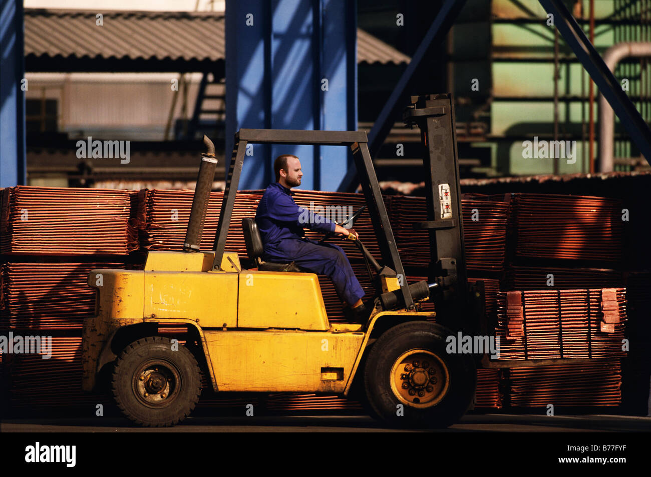 Worker lifting pallets of copper pipes on forklift Stock Photo - Alamy