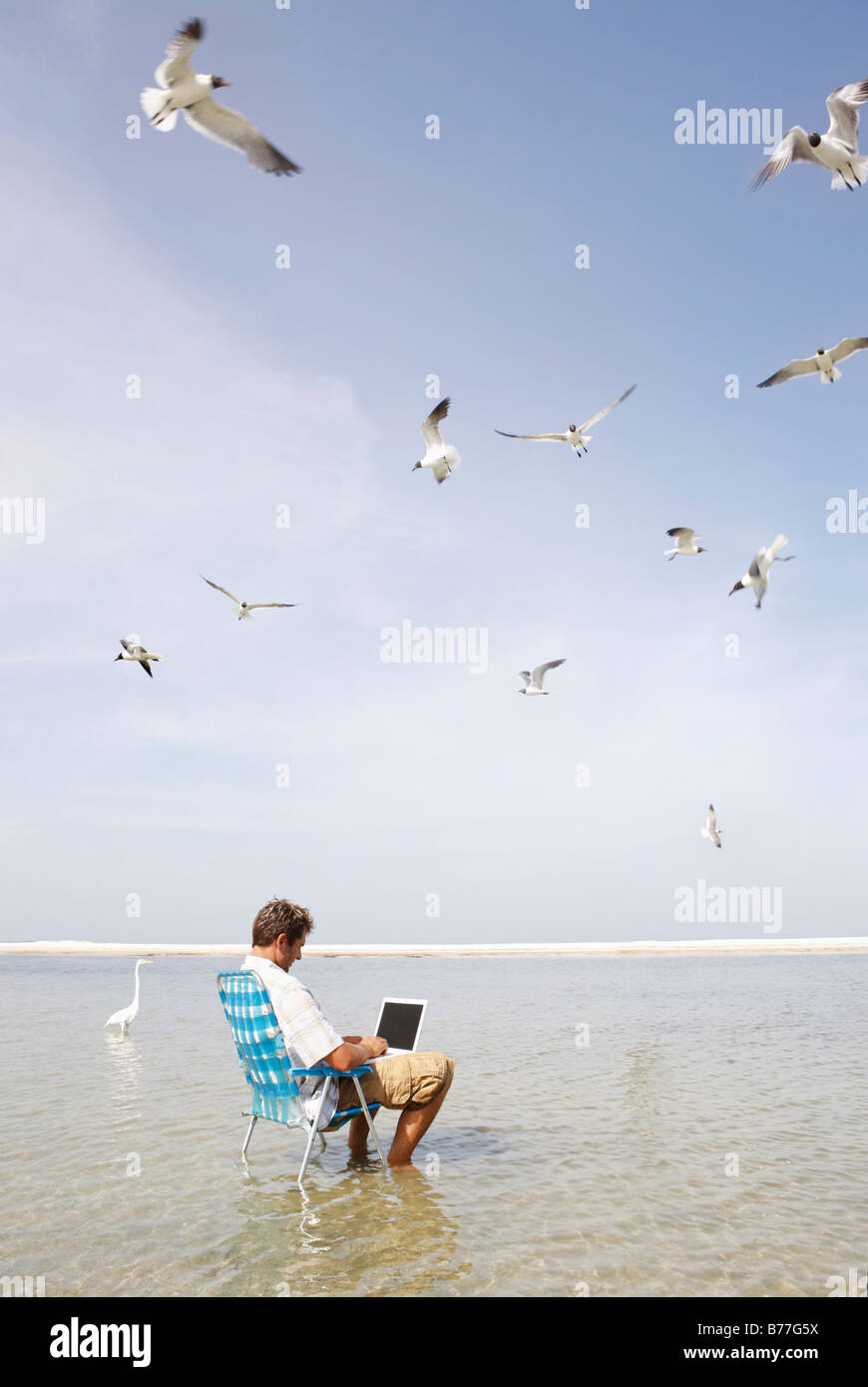 Man sitting ocean surf laptop Stock Photo - Alamy
